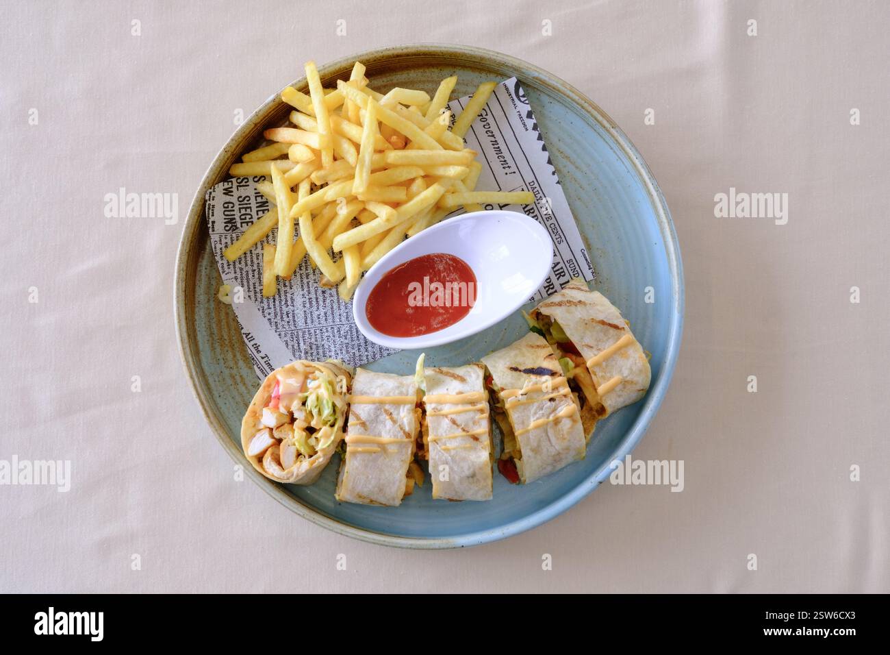 Grilled wrap cut into pieces served with french fries and a side of ...