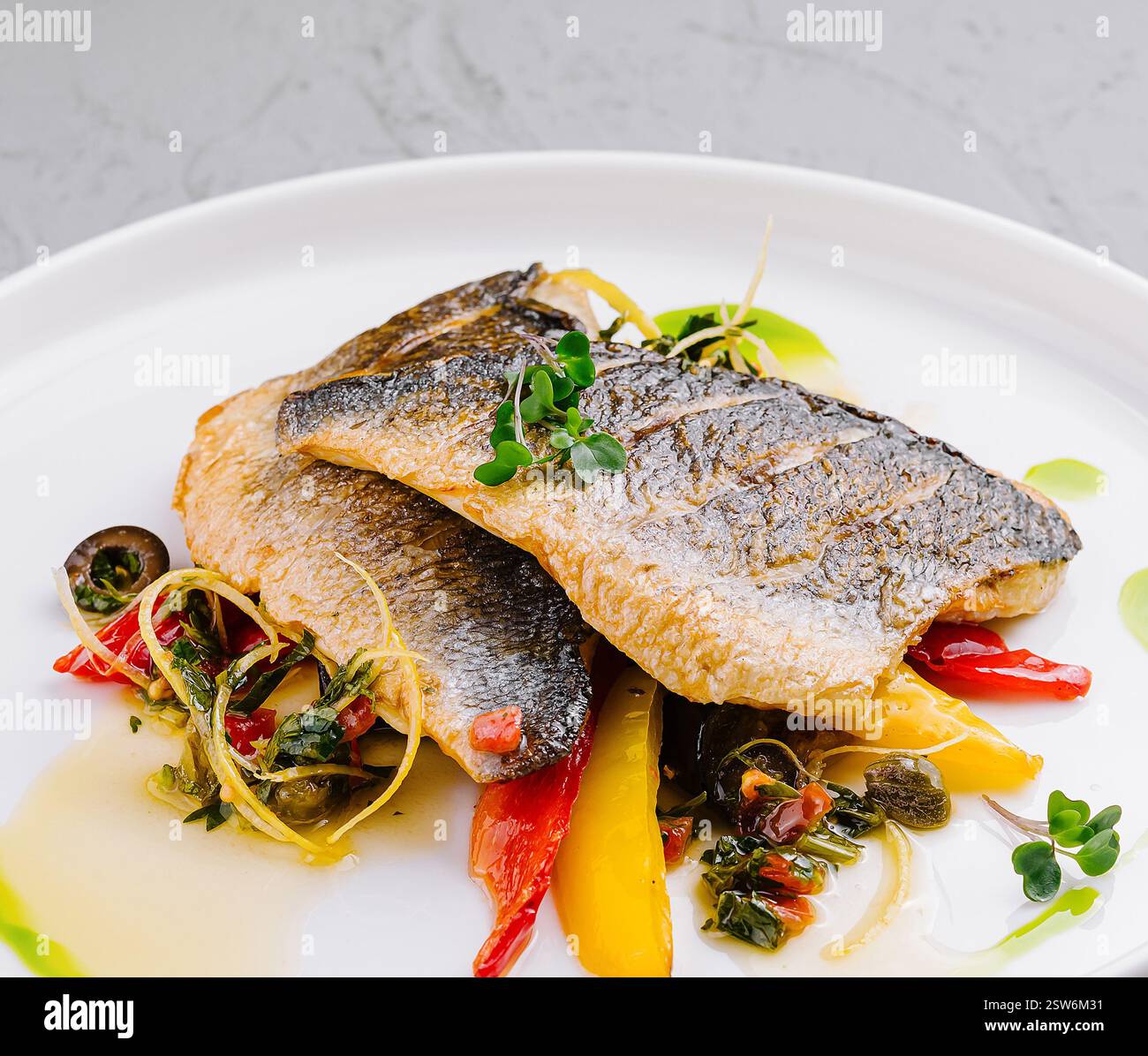 Gourmet pan-seared fish with vegetable garnish Stock Photo - Alamy