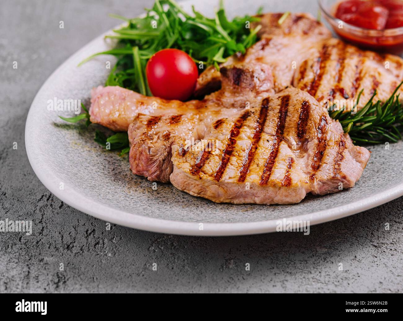 Grilled pork chops on ceramic plate with herbs Stock Photo - Alamy