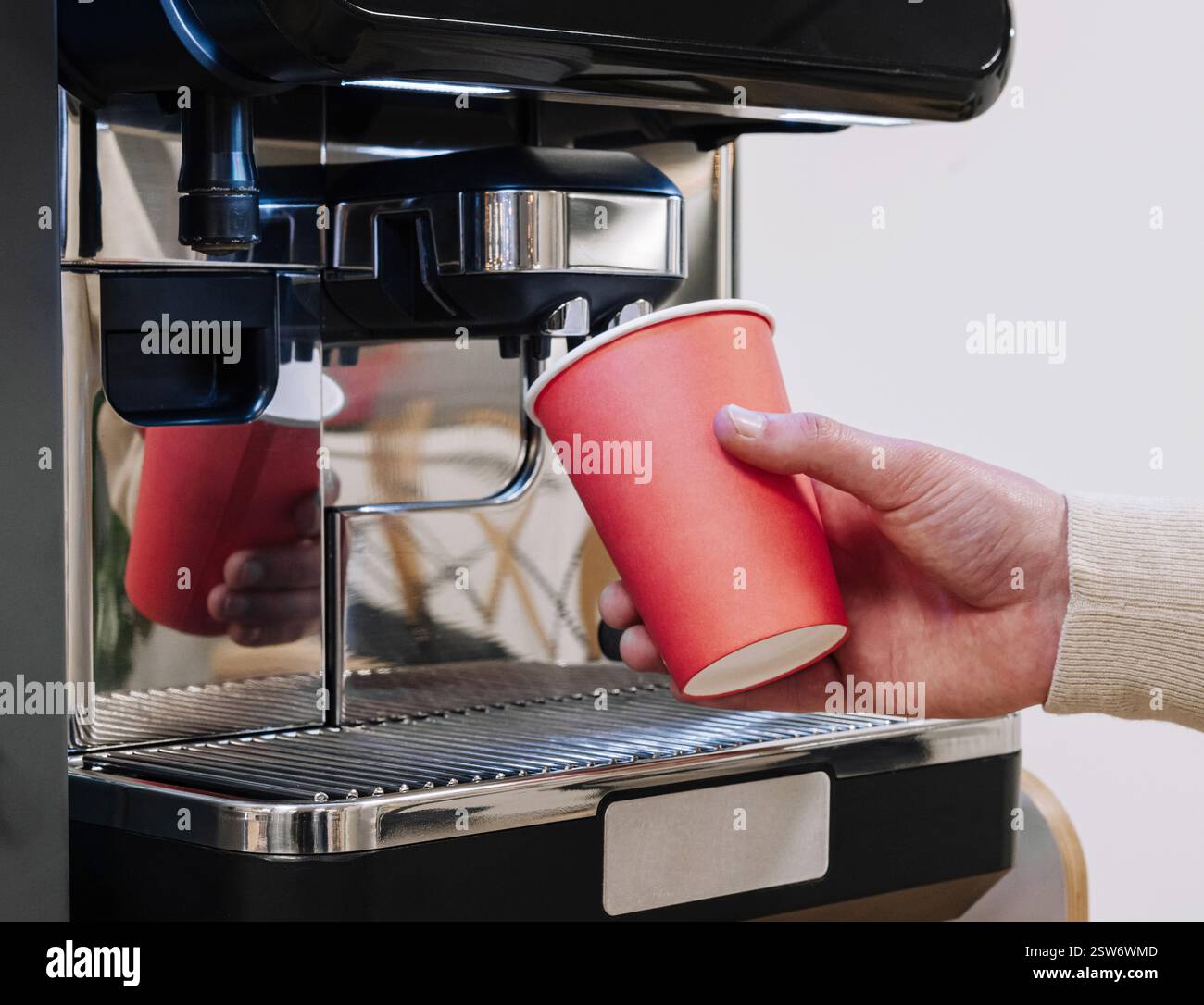 Hand filling red cup at coffee machine Stock Photo - Alamy
