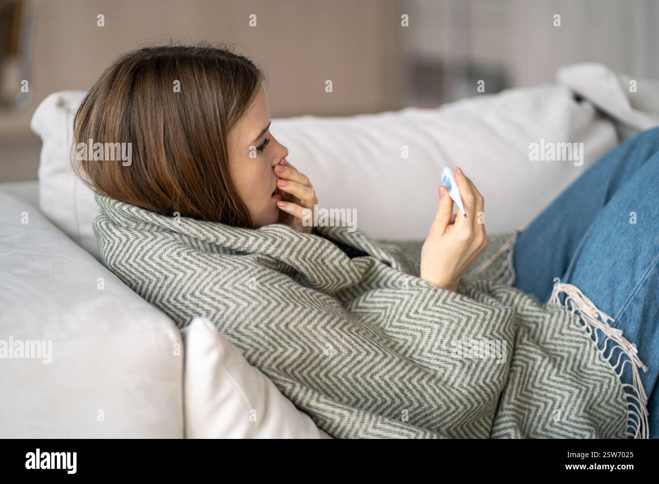 Sick woman holding head in pain, checking temperature with thermometer ...