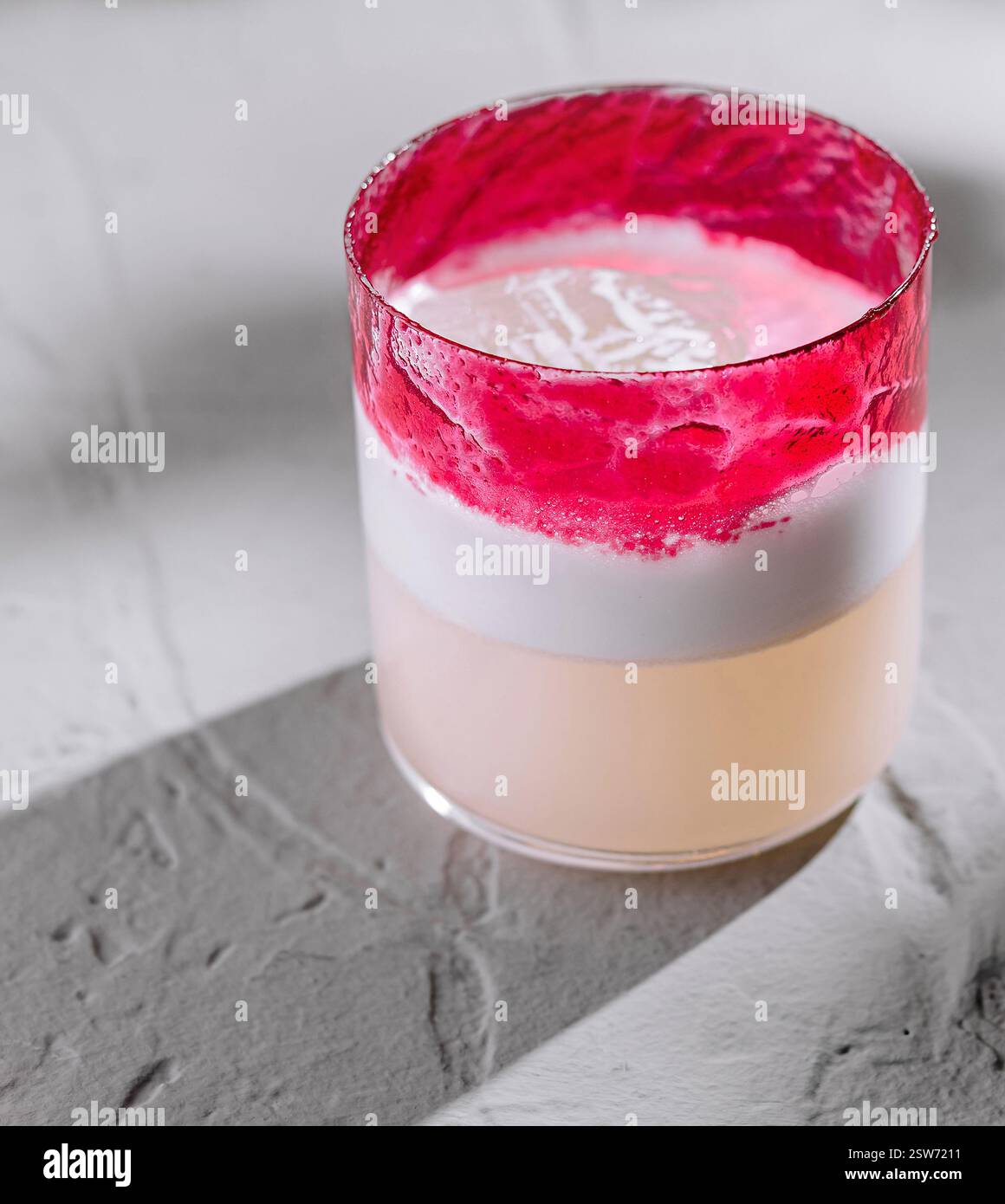 Stylish cocktail with vibrant pink and white layers, presented on a ...