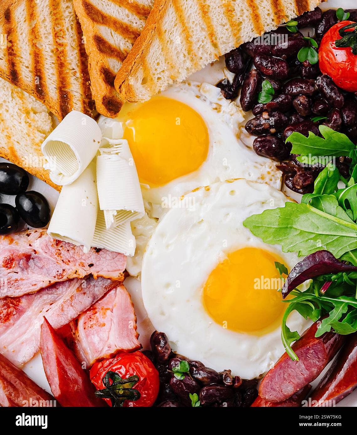 Overhead view of a hearty breakfast plate with eggs, bacon, toast, and ...
