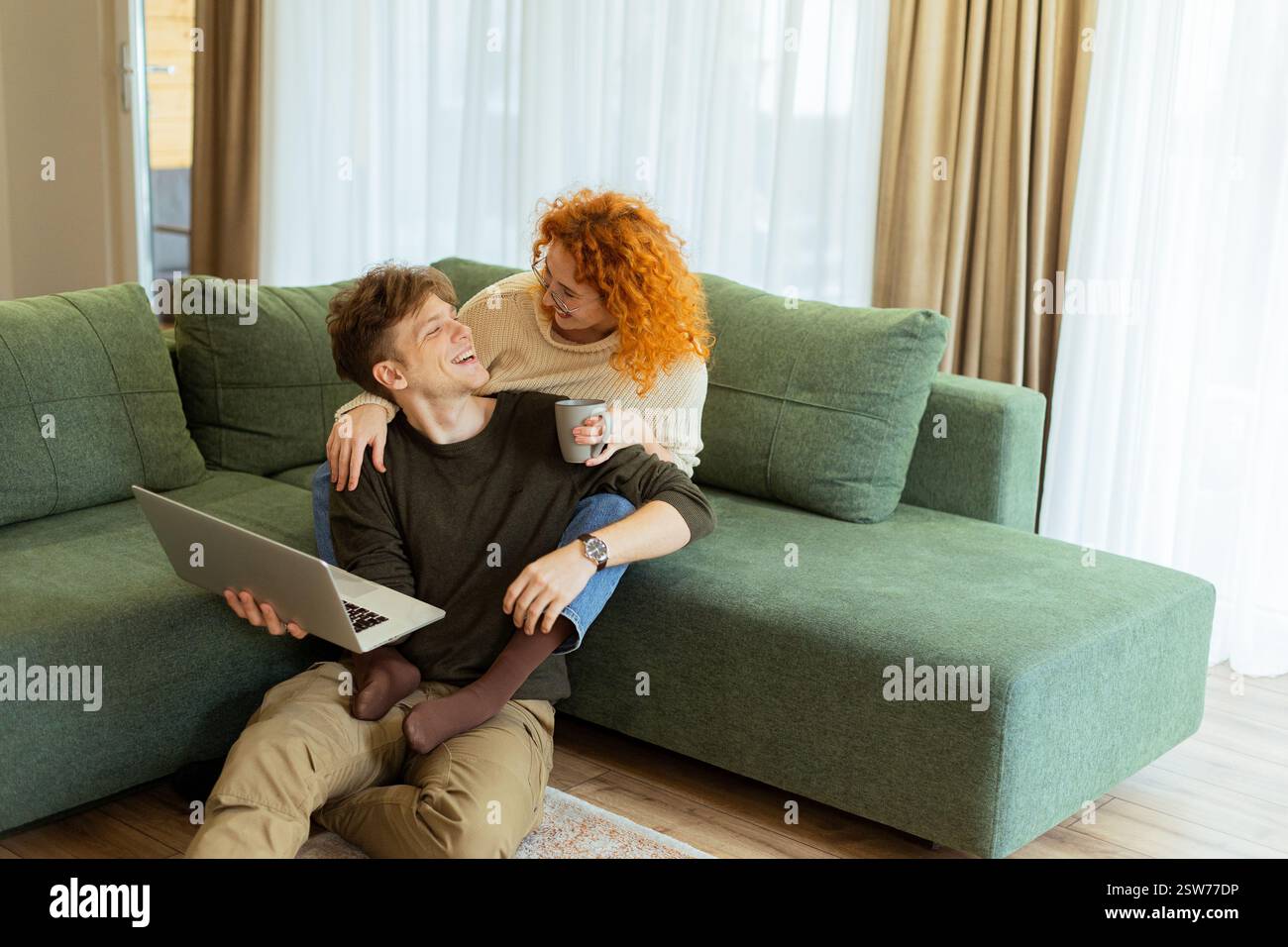 Two friends engage in a light-hearted moment at home, seated ...