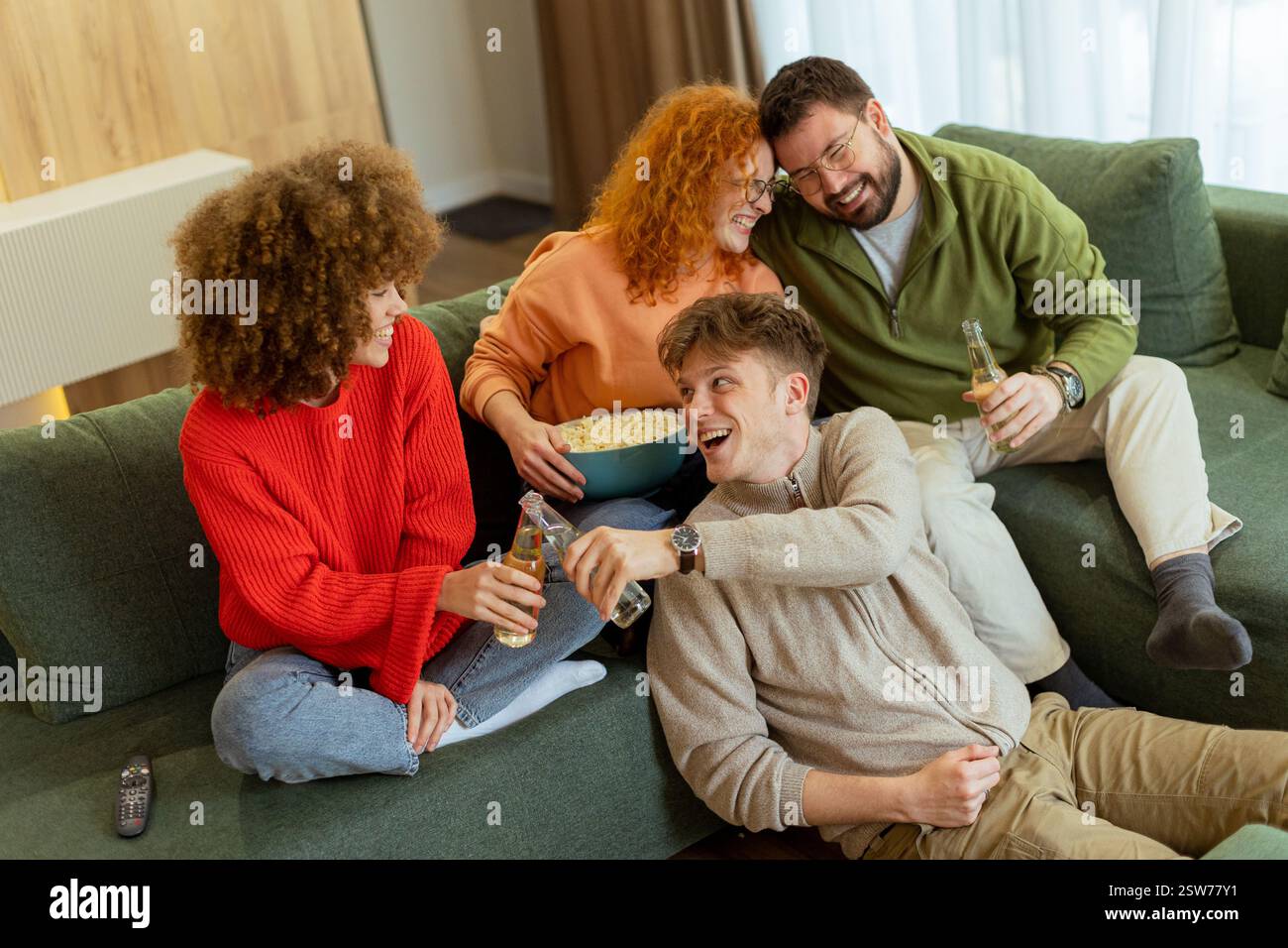 Laughter fills a well-lit living room as four friends share a joyful ...