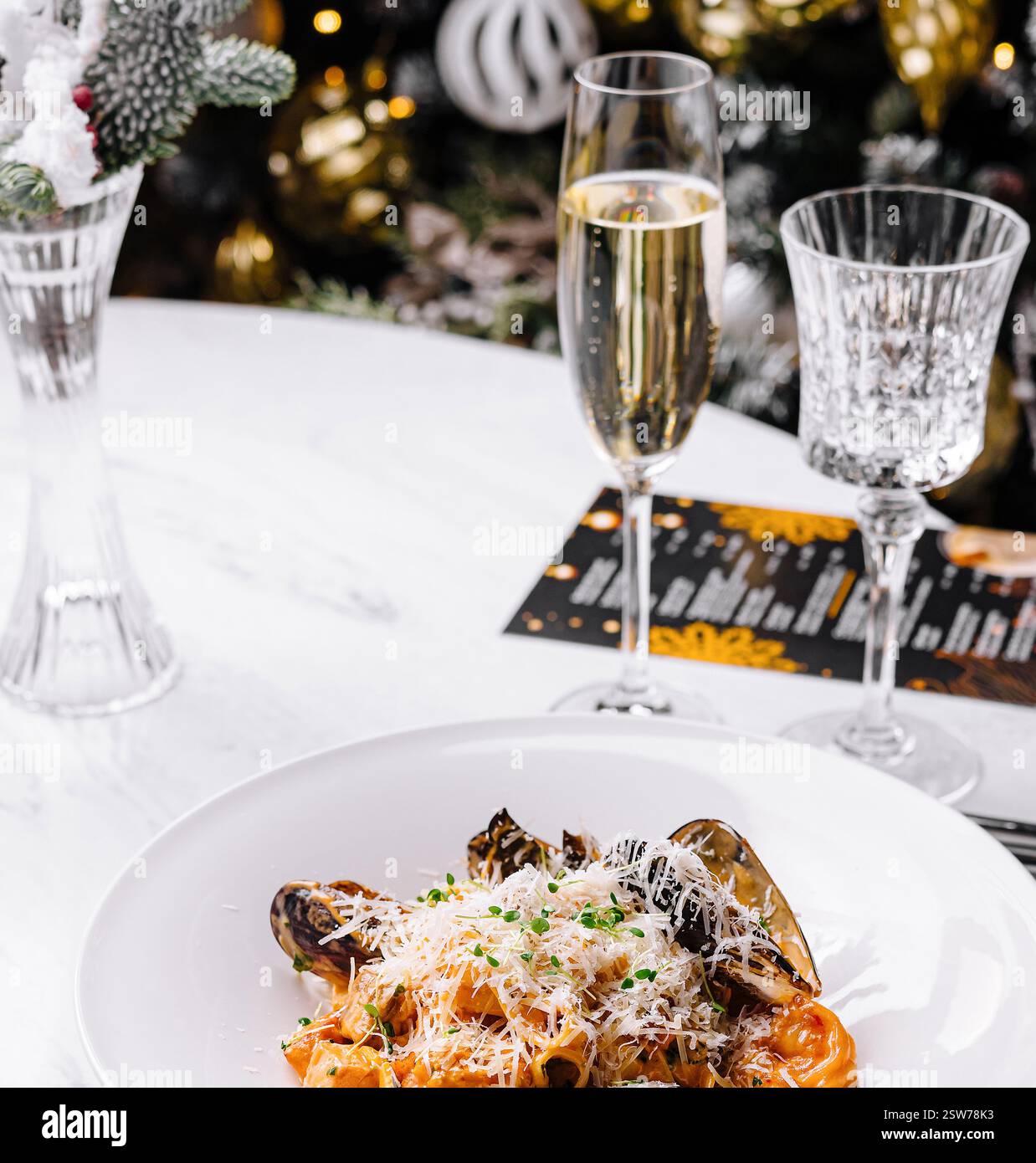 Gourmet mussel pasta is served on a luxurious dining table with a glass ...