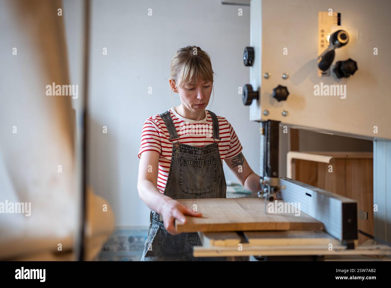Female joiner use jigsaw and lathe, cut wood piece into required shape ...