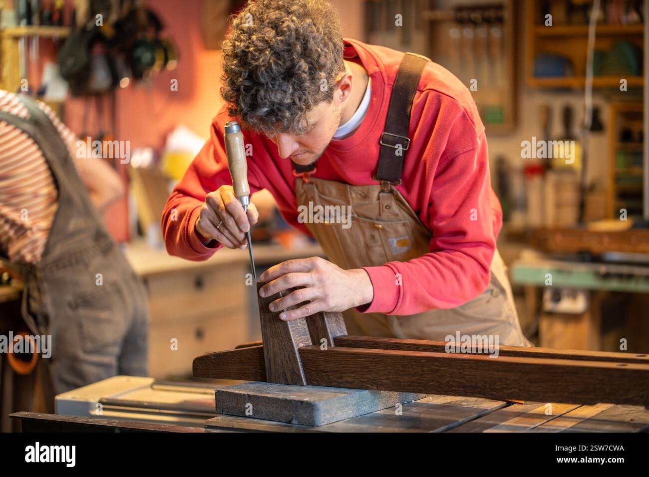 Focused carpenter immersed in work use chisel to smooth bed legs, makes ...