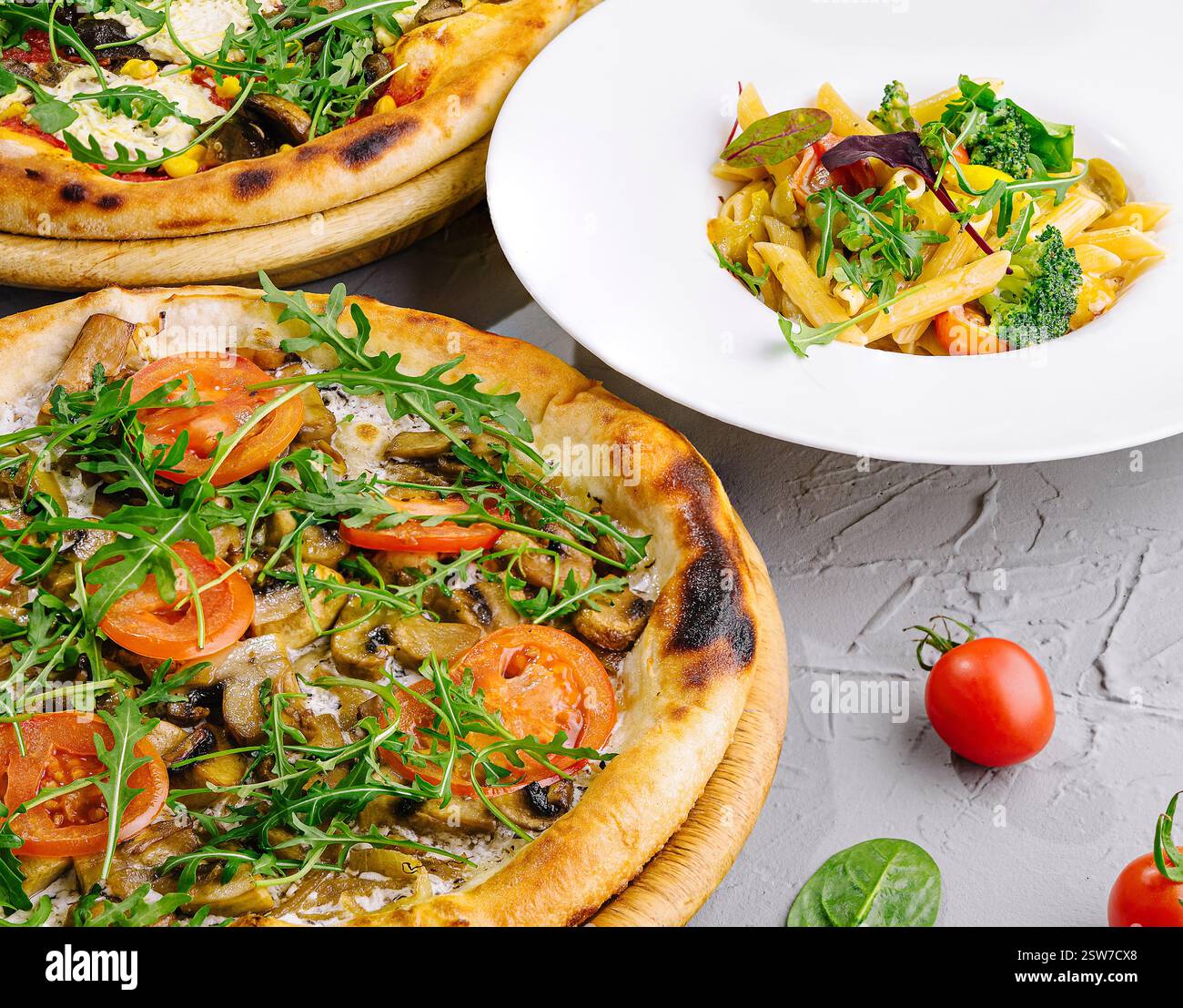 Artisanal pizzas with fresh toppings next to a plate of pasta, ready ...