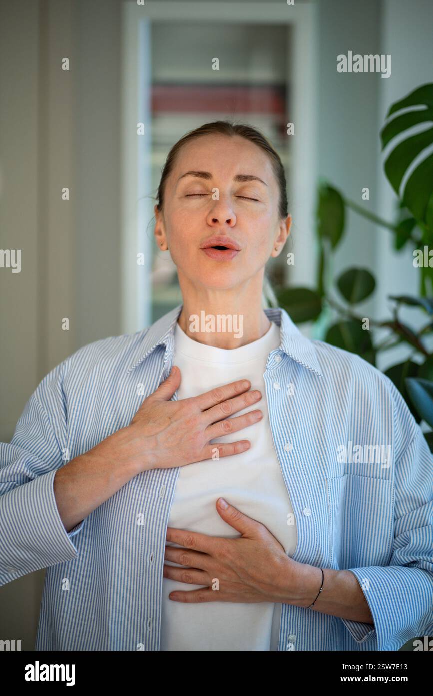 Focused on breathing middle aged woman holding hands on chest and belly ...