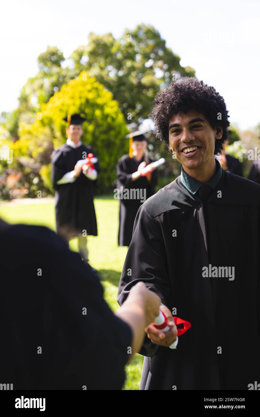 Receiving diplomas in garden, teen diverse graduates celebrating with ...