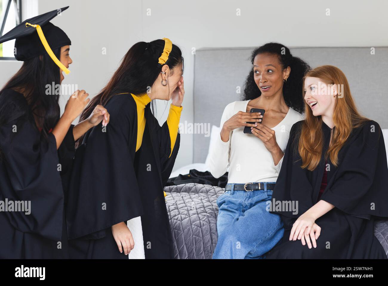 Diverse graduates in caps and gowns laughing and celebrating with woman ...
