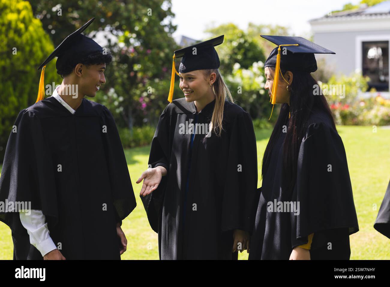 Graduating diverse students in caps and gowns celebrating together in ...