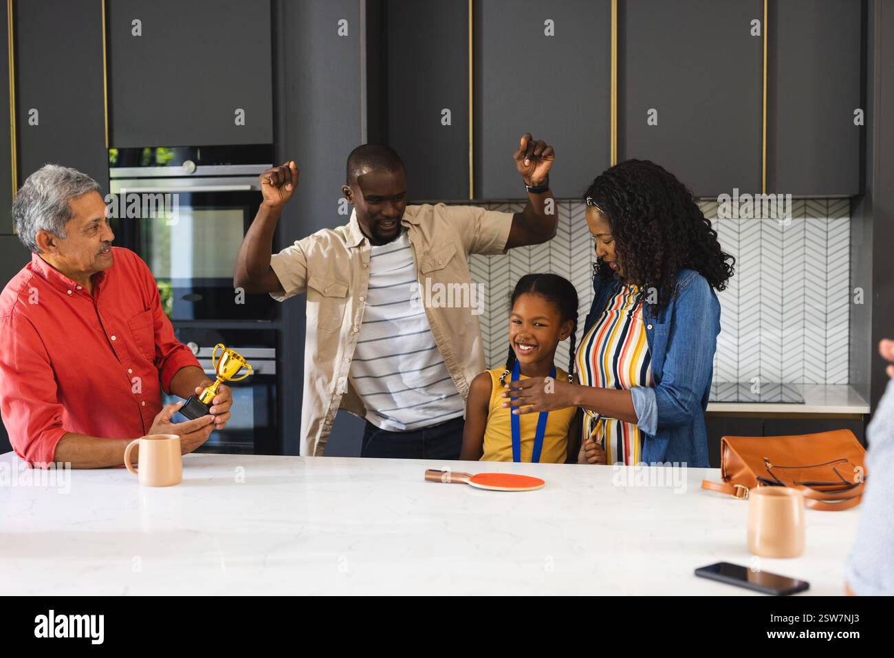 Celebrating child's achievement, diverse family smiling and cheering ...