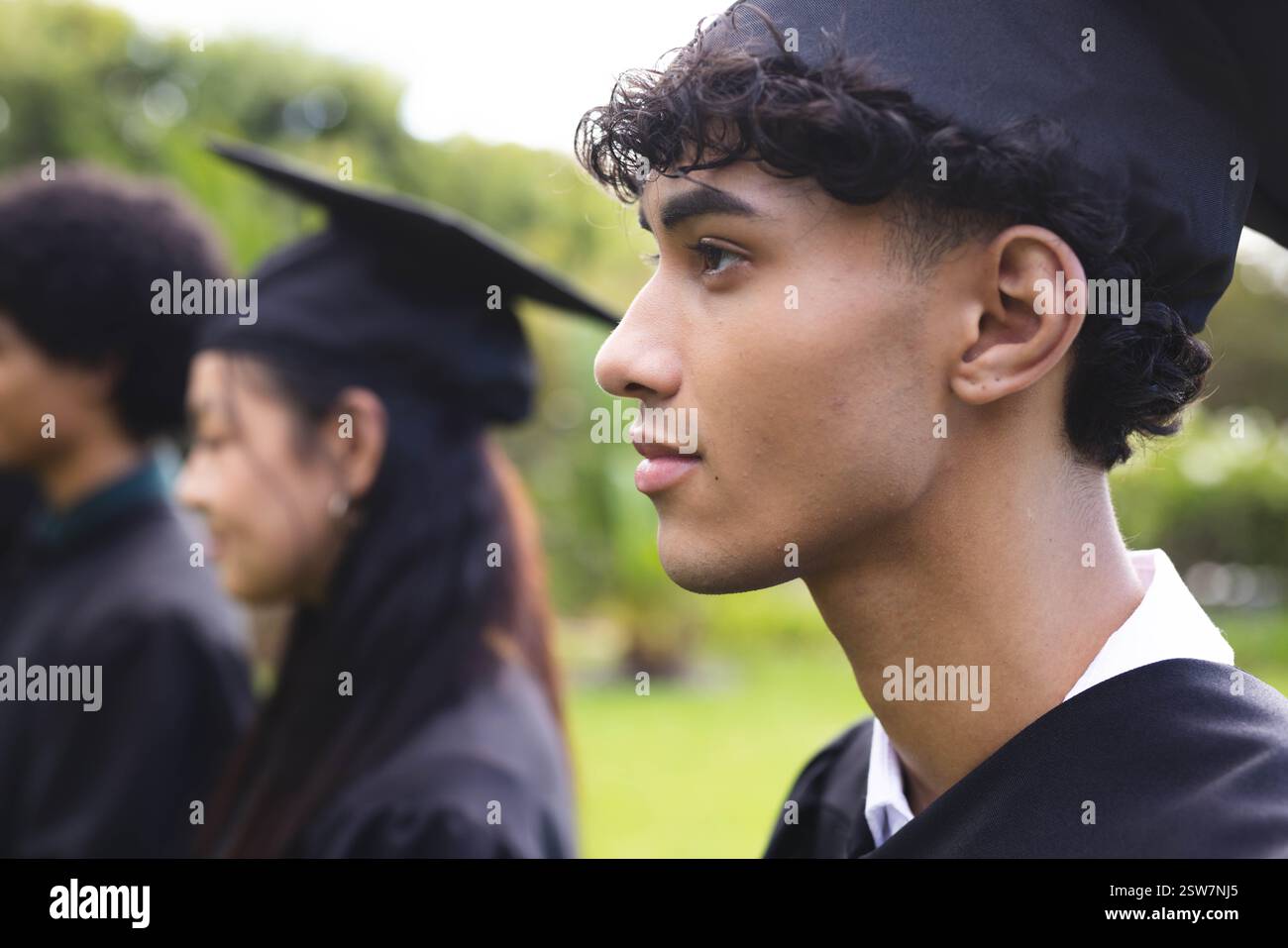 Teen diverse graduates in caps and gowns celebrating success in garden ...