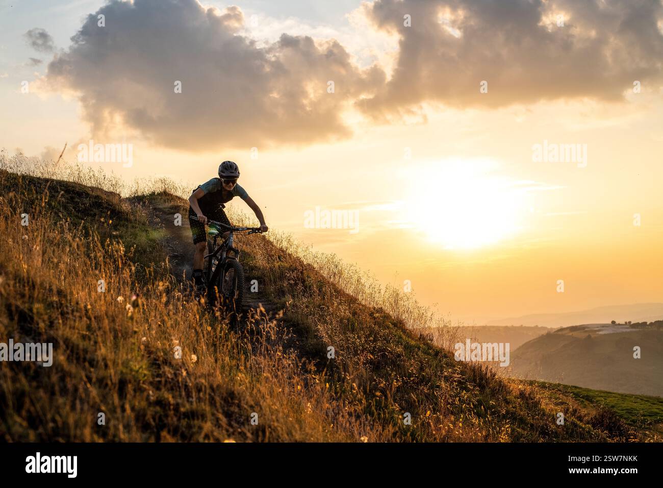A woman rides a mountain bike at sunset in the south Wales valleys during the summer Stock Photo ...