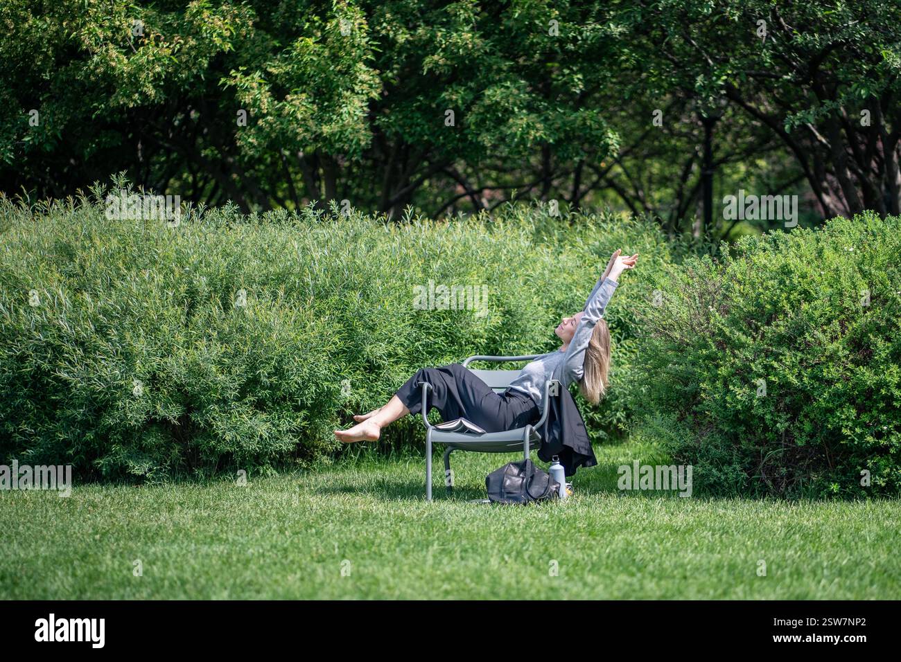 Carefree woman relaxing on park chair surround lush plants barefoot ...