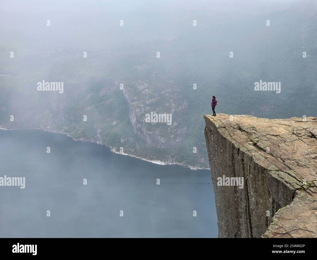 Adventurous Hiker Standing on Preikestolen Cliff Overlooking the Fjord ...