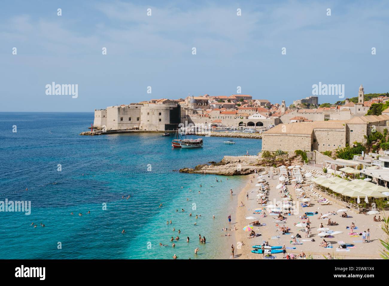 Visitors relax on the sandy beach beneath warm sun rays hi-res stock ...