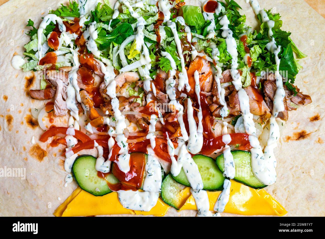 A vibrant wrap is filled with layers of lettuce, tomato, cucumber ...