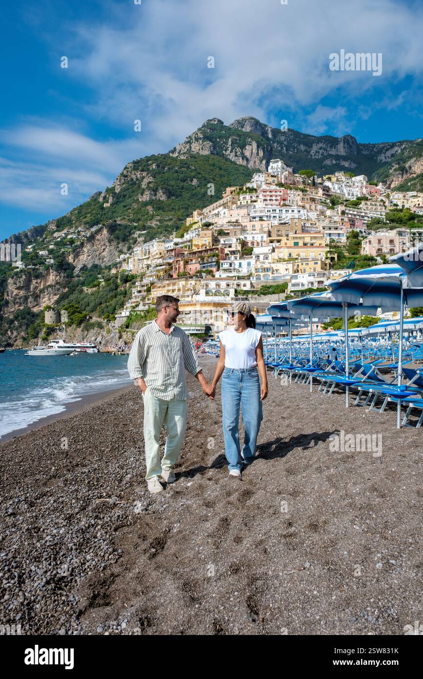 Couple strolling hand-in-hand along the pebbled beach of Positano on ...