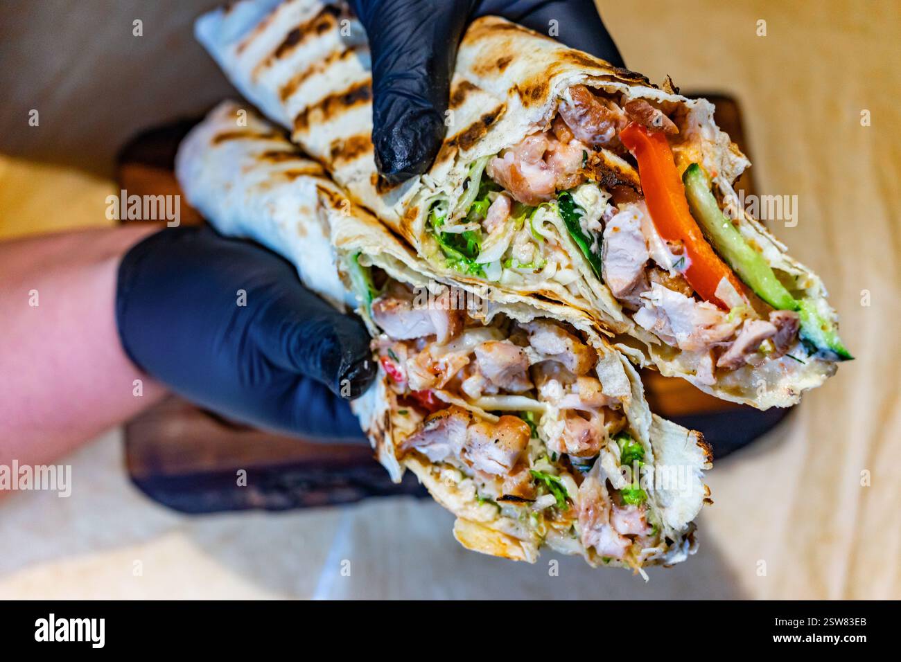 Two grilled wraps are being held, showcasing a generous filling of ...