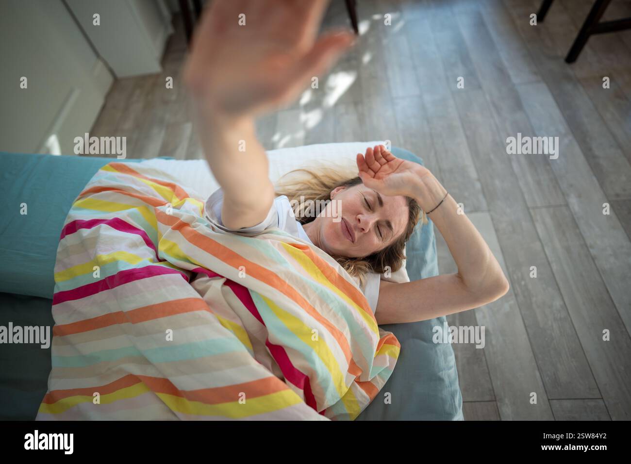 Relaxed mischief woman closes hand and want to stay in bed in morning ...