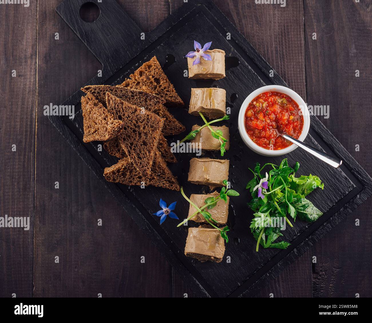 Slices of chicken liver pate decorated with flowers on black board ...