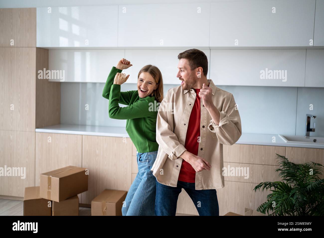 Happy couple dancing back to back, celebrating housewarming, moving in ...