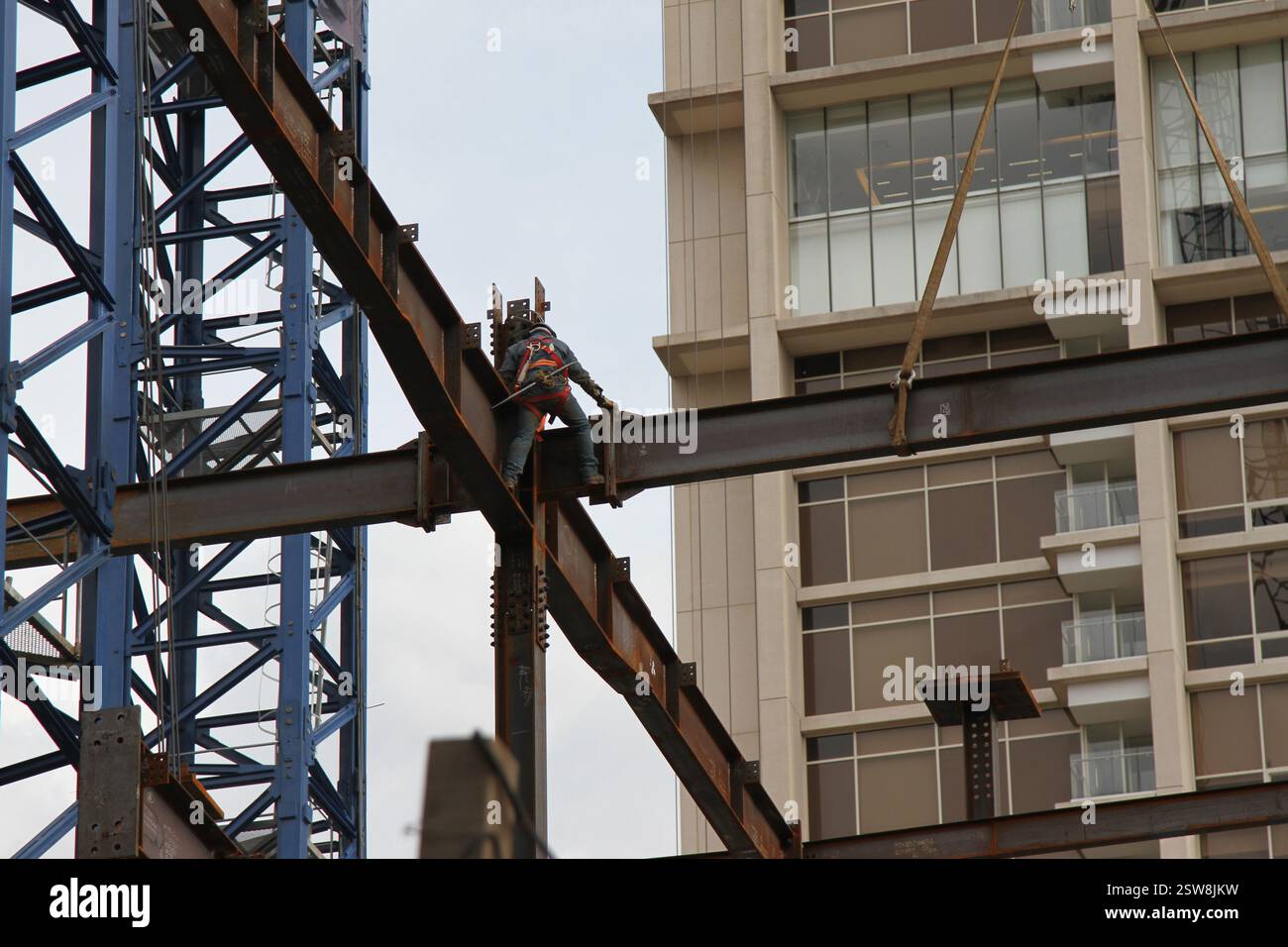 A construction worker walking on the edge of a steel beam Stock Photo ...