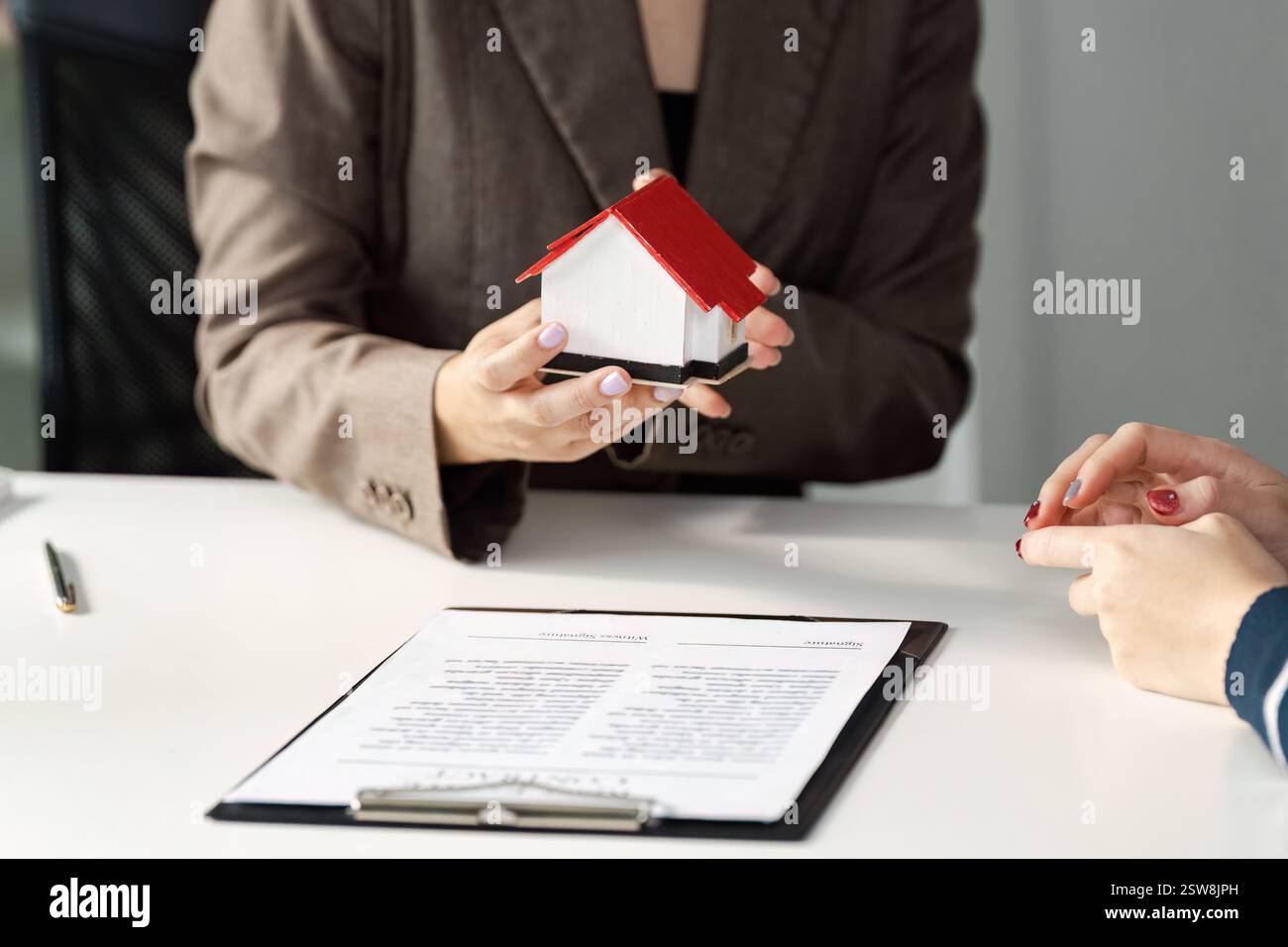 Real estate agent presenting model house to client, discussing property ...