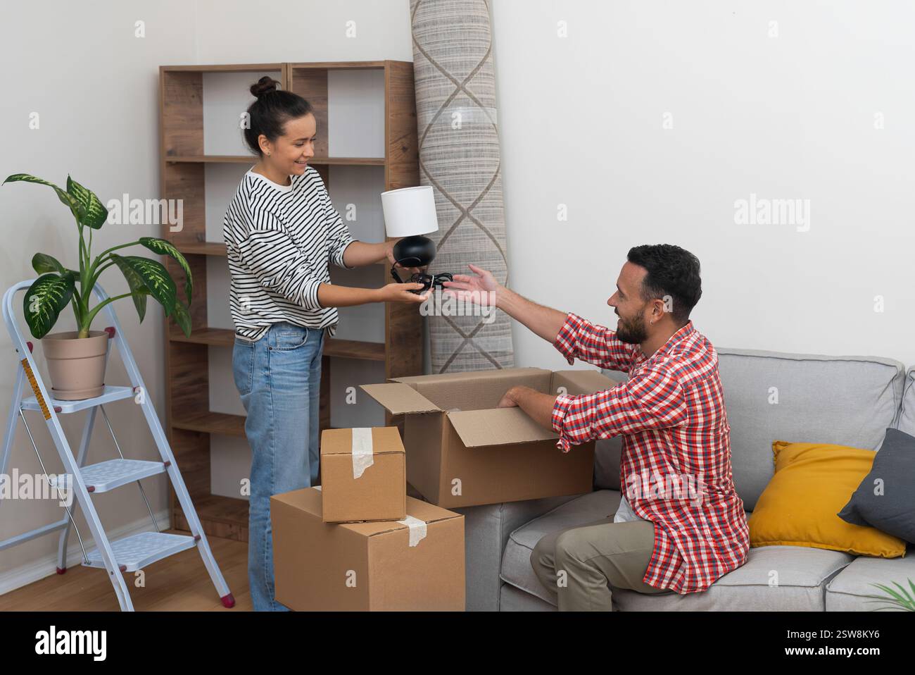 husband and wife, moving into new residence, placing empty shelf and ...