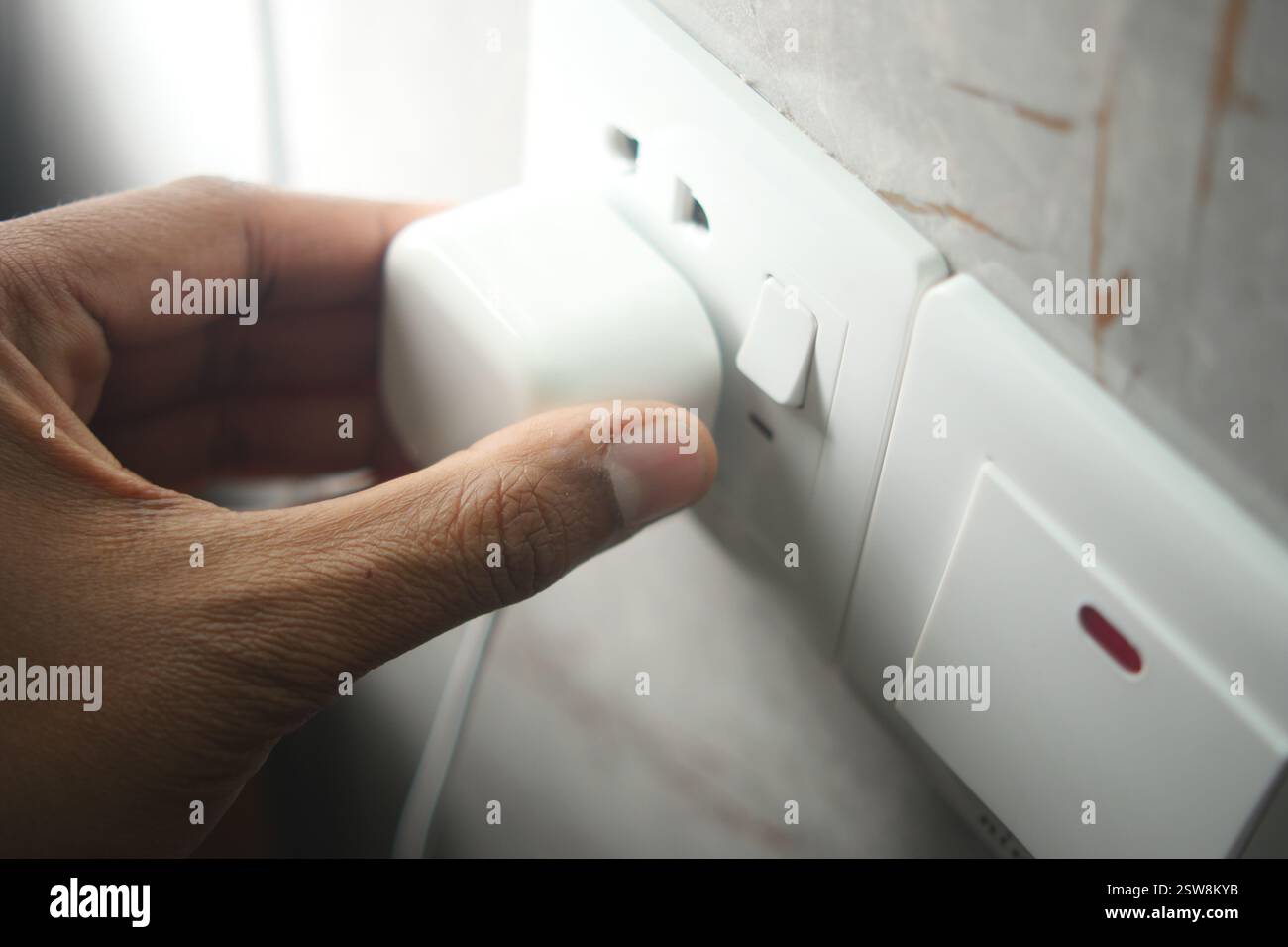 Hand plugging in a charger into a power outlet at home Stock Photo - Alamy