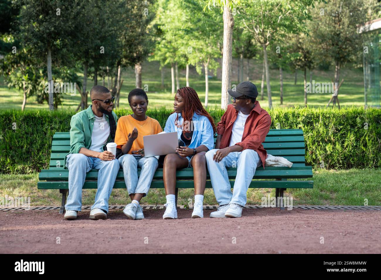 Four students relaxing together outside having pleasant conversation ...