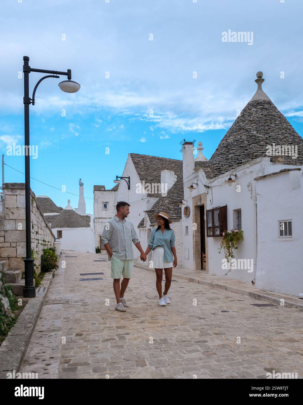 Couple strolling hand in hand through charming streets of Puglia, Italy ...