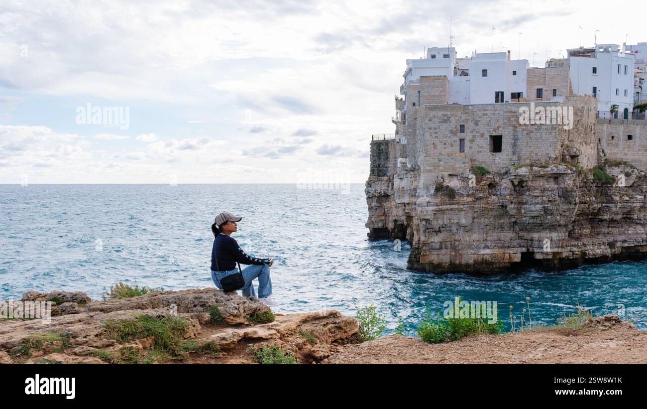visitor sits peacefully on a rocky ledge, gazing at the breathtaking ...
