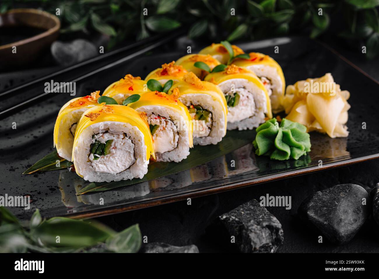 Mango sushi rolls presenting filling on dark plate with wasabi and ...