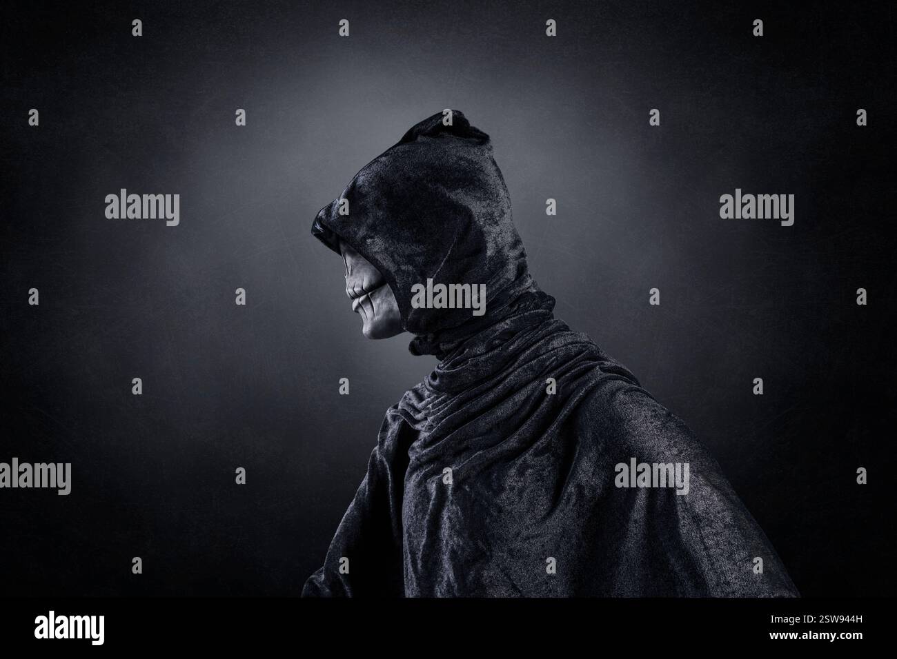 Scary figure with hooded cloak over dark misty background with clipping ...