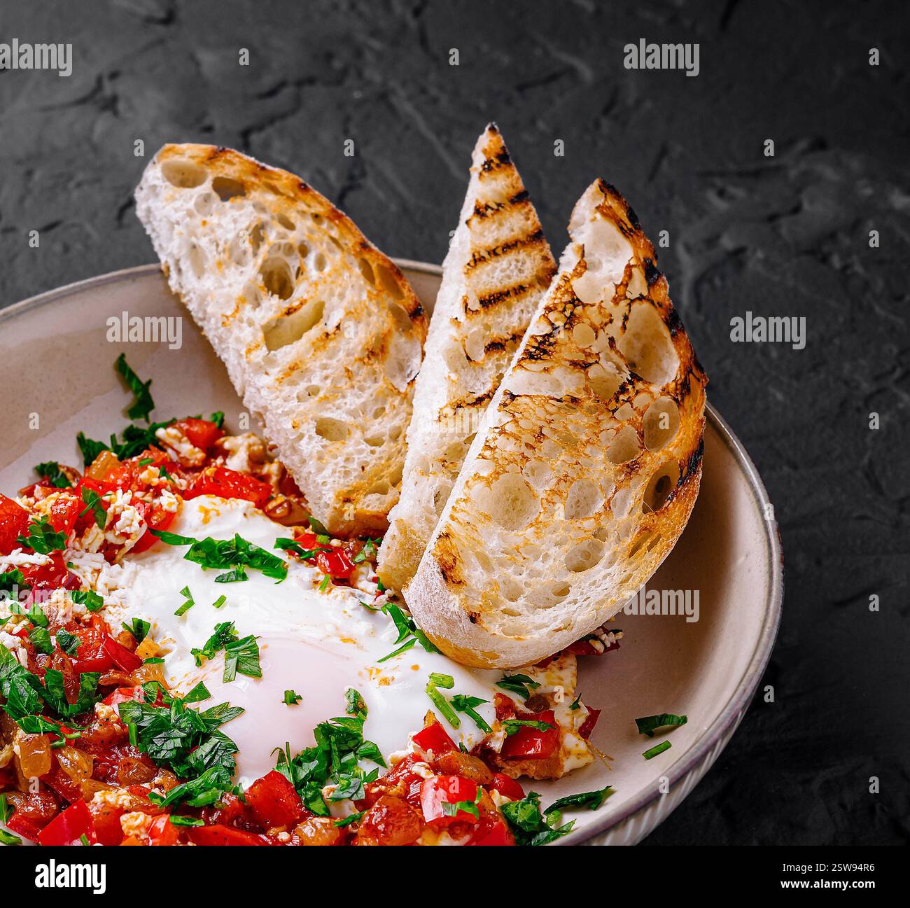 Delicious shakshuka with toasted bread on dark background Stock Photo ...