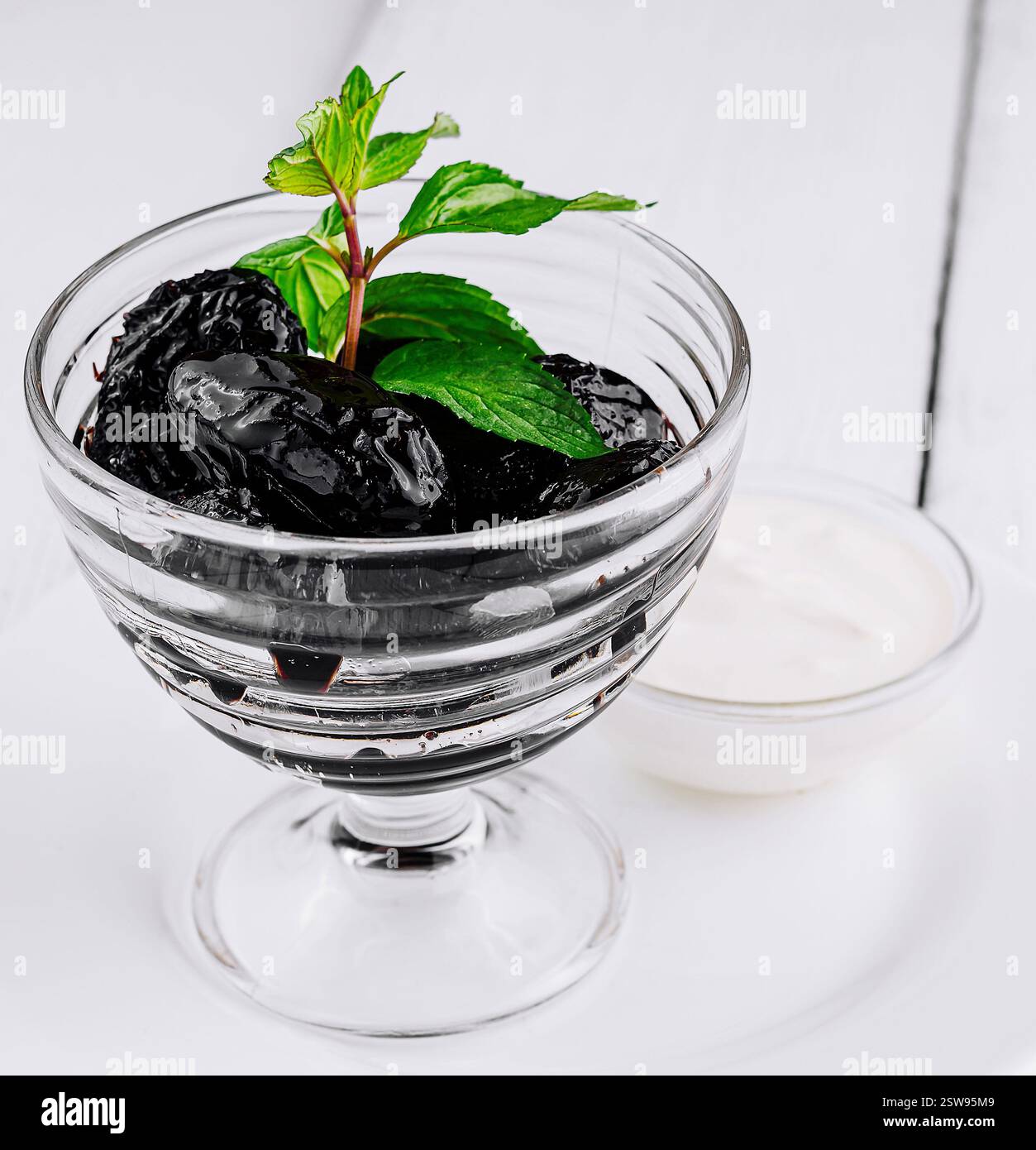Prunes with mint sprig served in glass on white table Stock Photo - Alamy