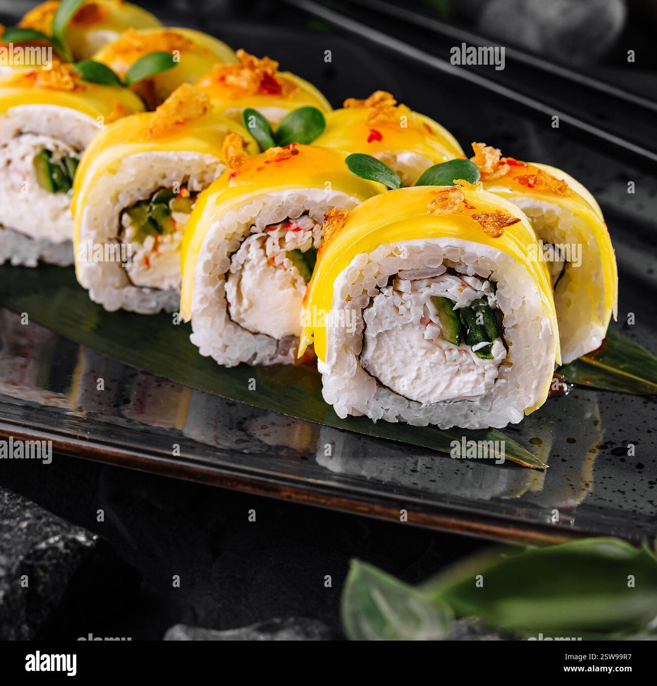 Mango sushi rolls presenting filling on dark plate with wasabi and ...