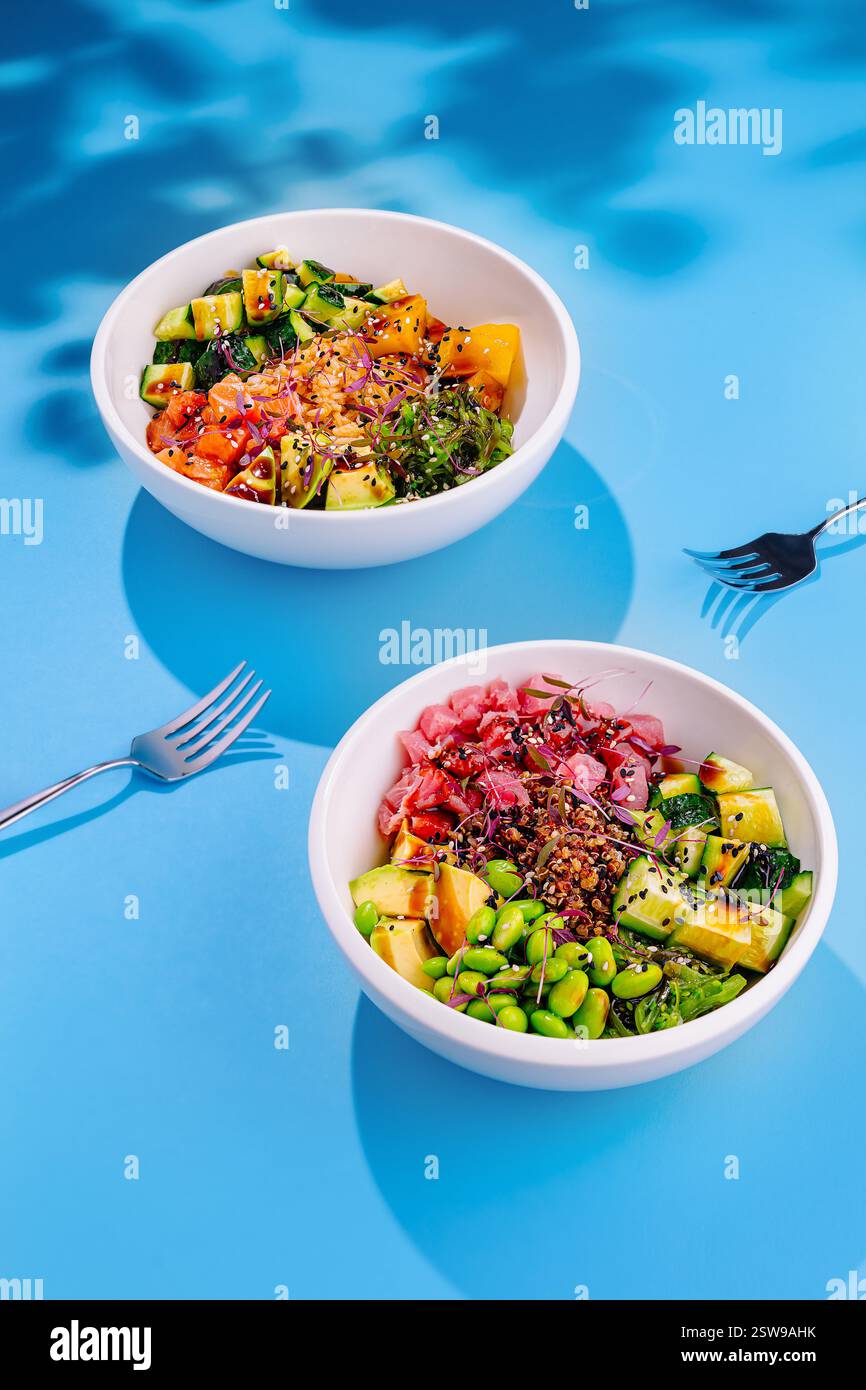 Two colorful bowls of poke on a vibrant blue background with forks ...
