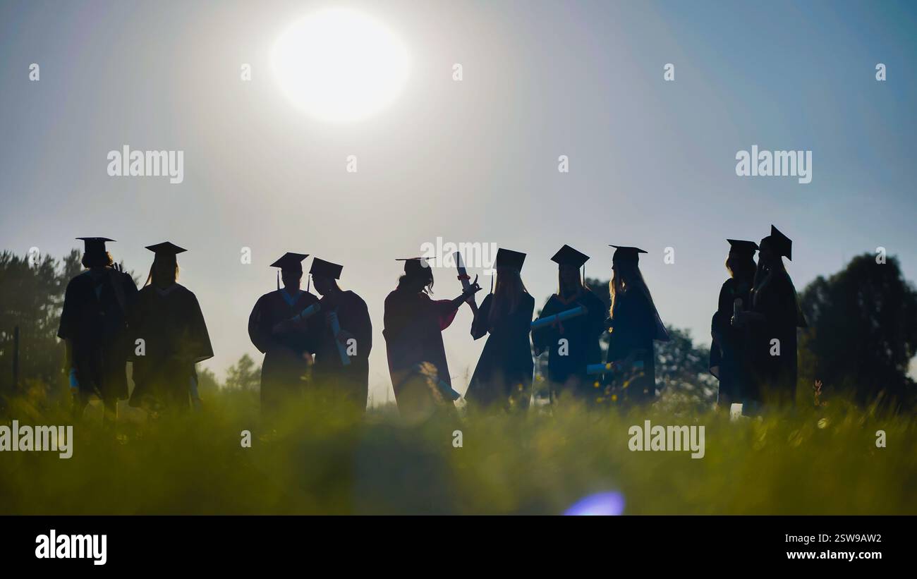 Silhouetted graduates holding diplomas, celebrating their academic ...