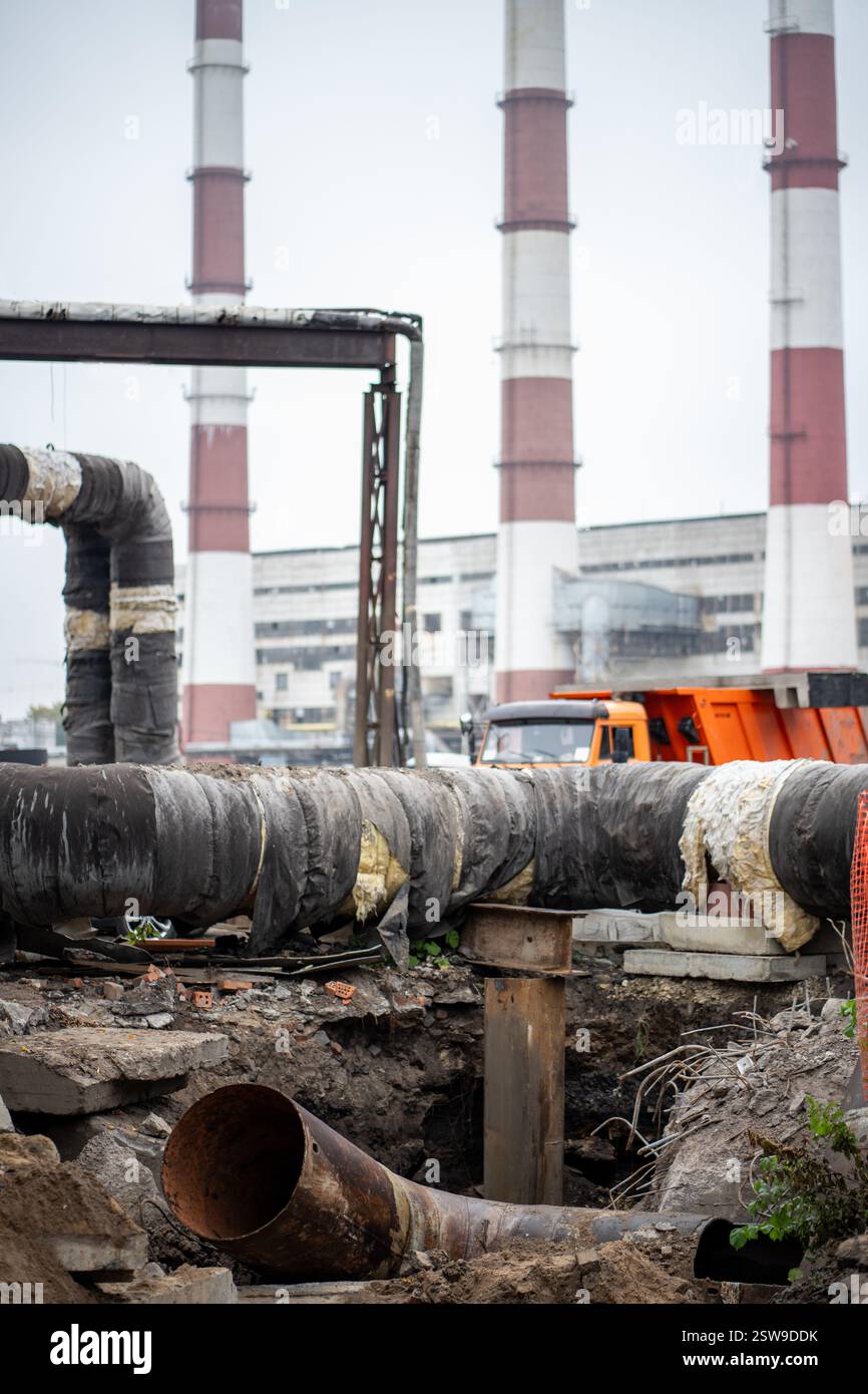 Dug trench on construction site with smokestacks behind. Pipe ...