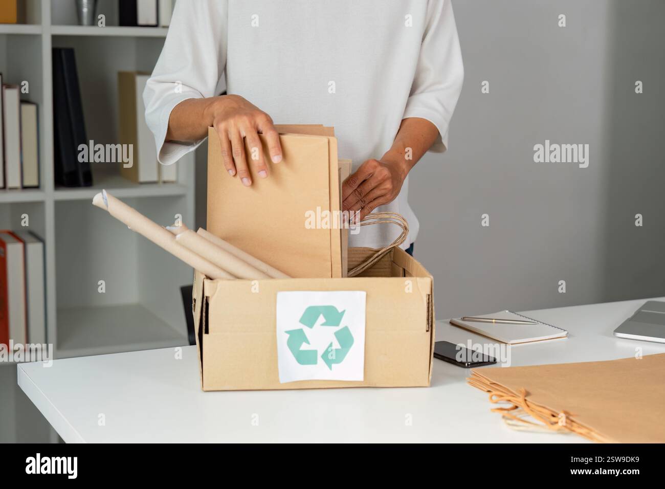 Person placing recycled paper and materials into a recycling box ...