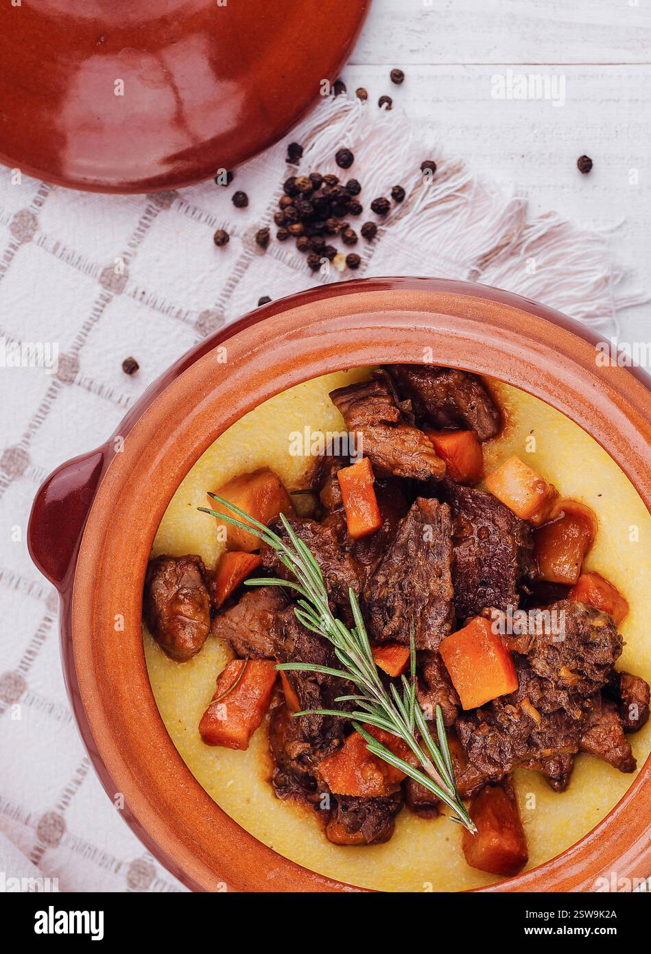 Stewed beef with polenta and vegetables in rustic earthenware dish ...