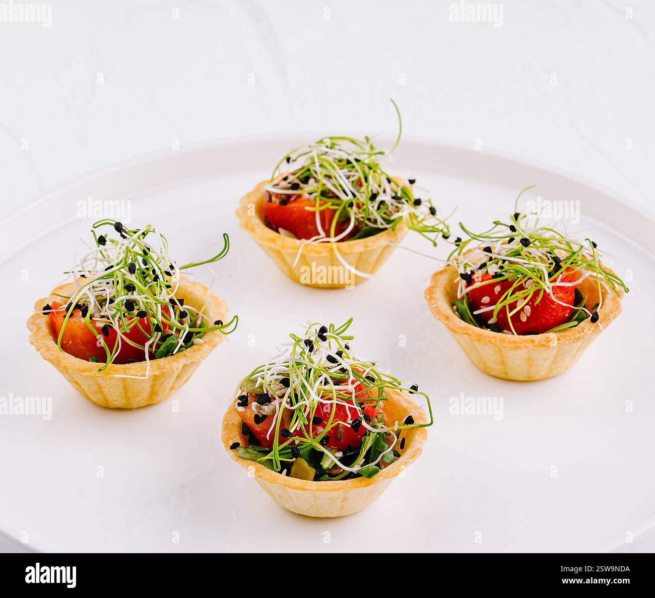 Elegant canapes with juicy tomatoes and delicate microgreens on a white ...