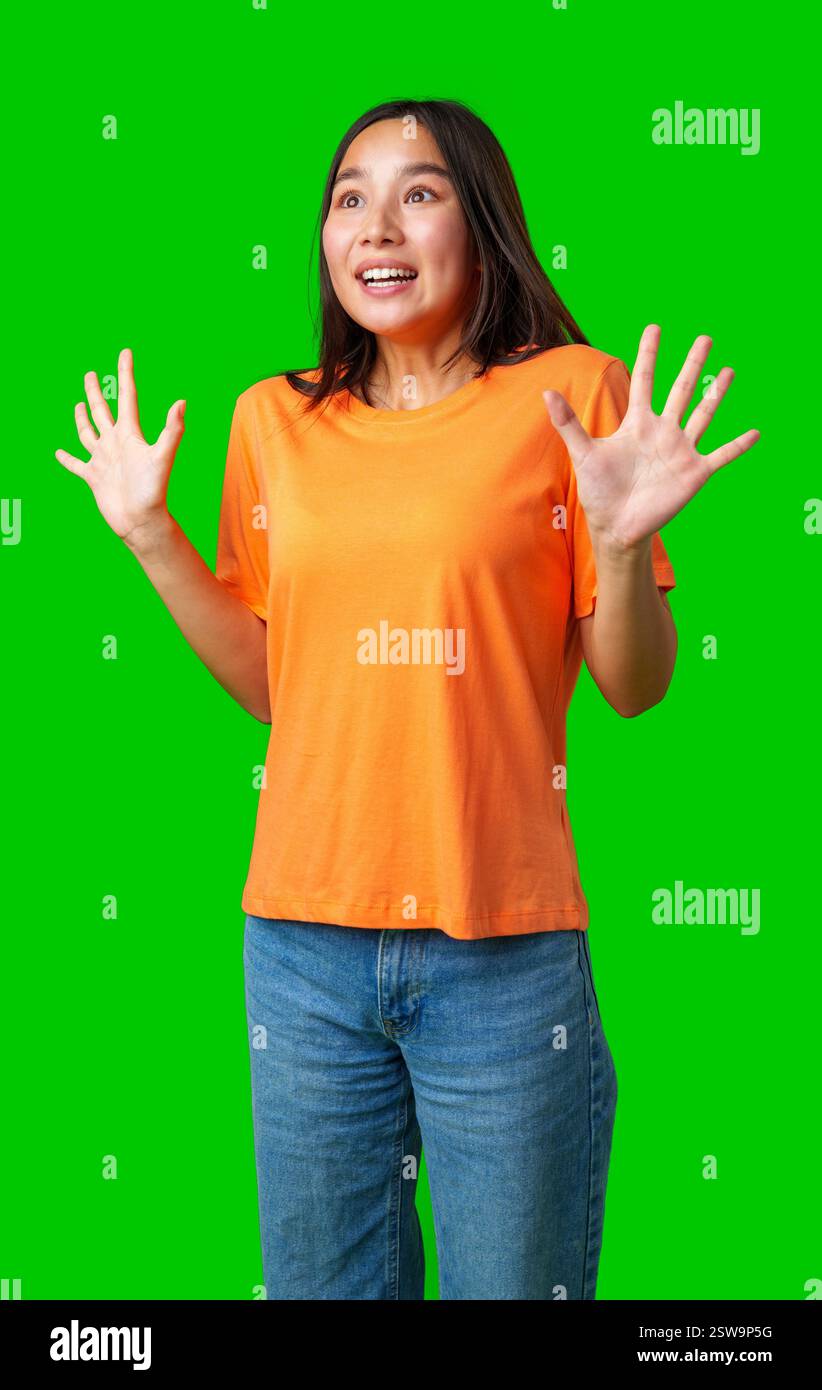 Excited young woman expresses joy and surprise against a vibrant green ...