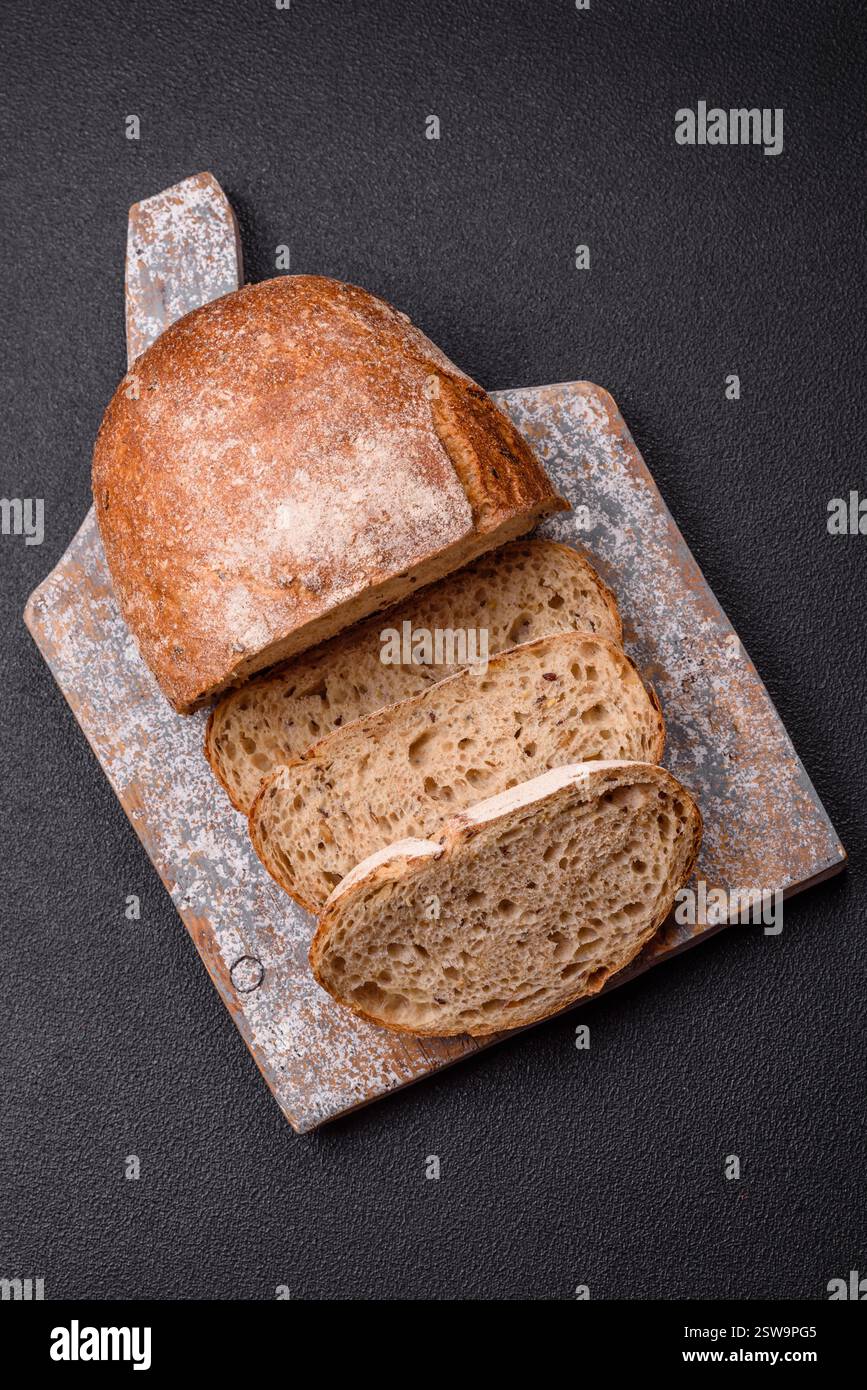 Brown bread with seeds and grains for sandwiches on a dark concrete ...