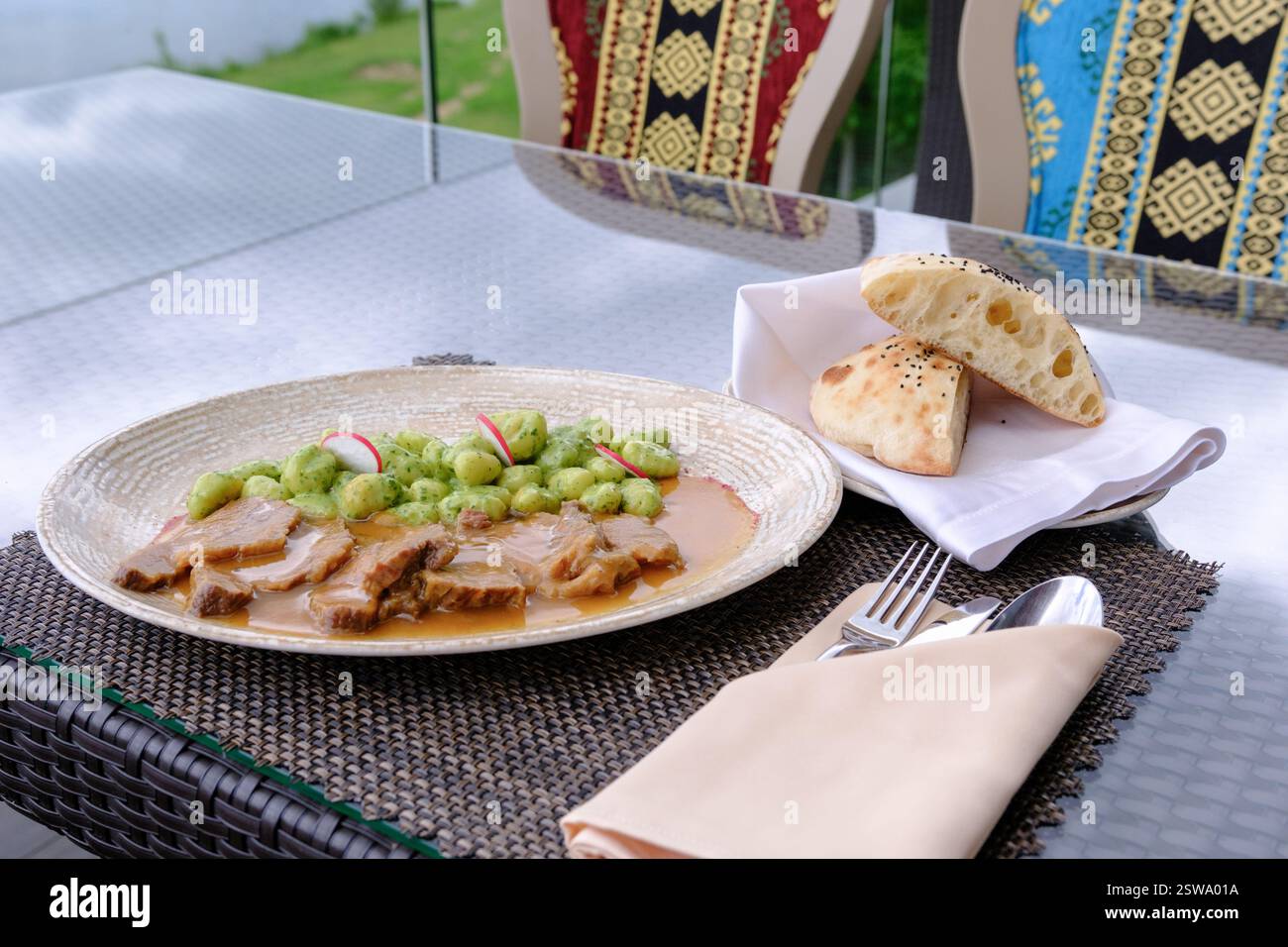 Sliced pot roast with herb gnocchi and a side of bread served outdoors ...